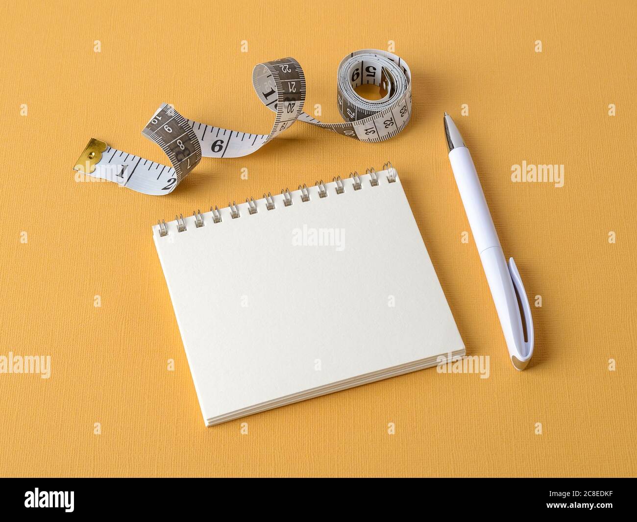 Open paper notepad with copy space, white pen and roll of measuring ...