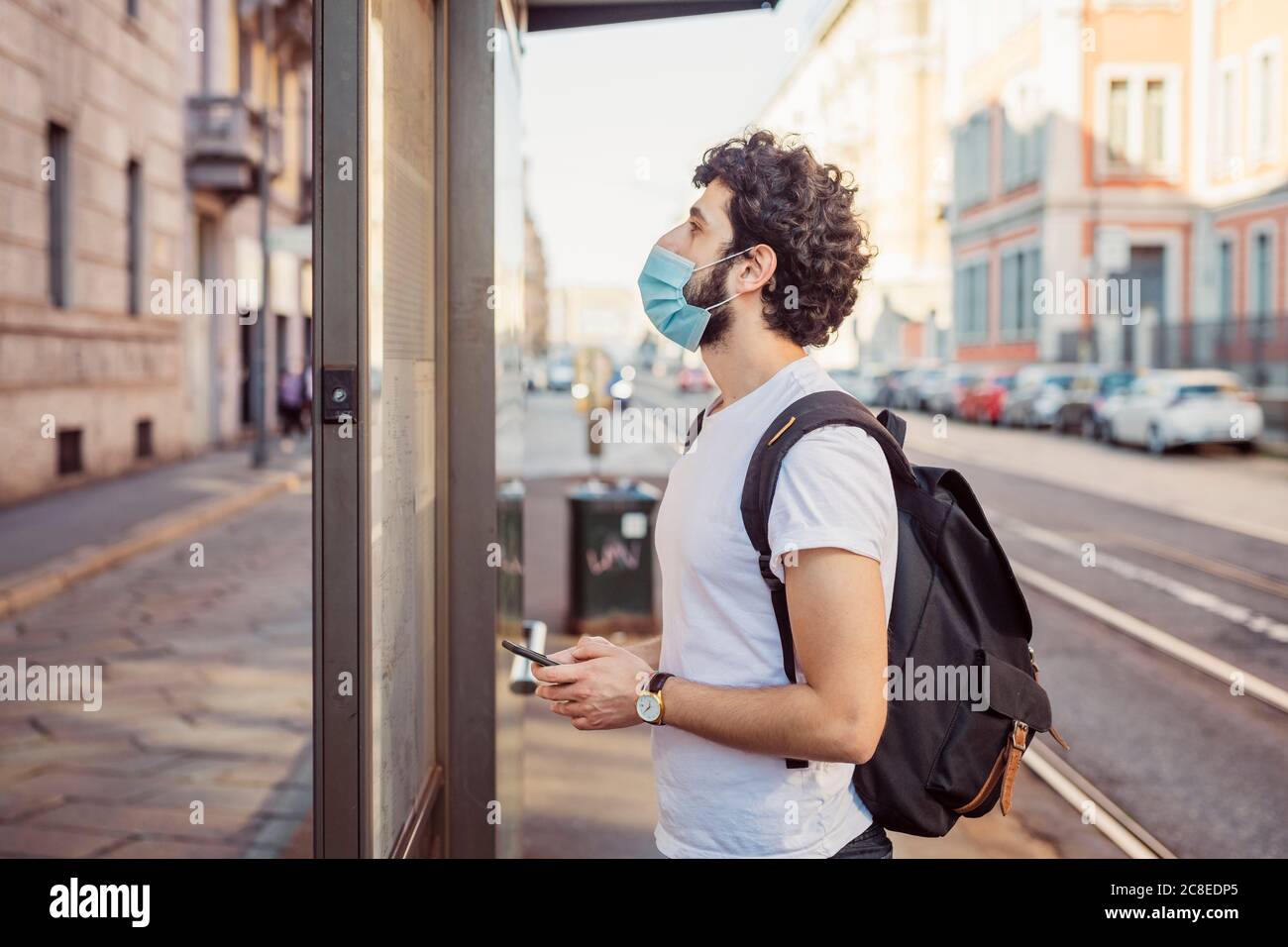 Young man wearing mask peeking through entrance of store Stock Photo ...