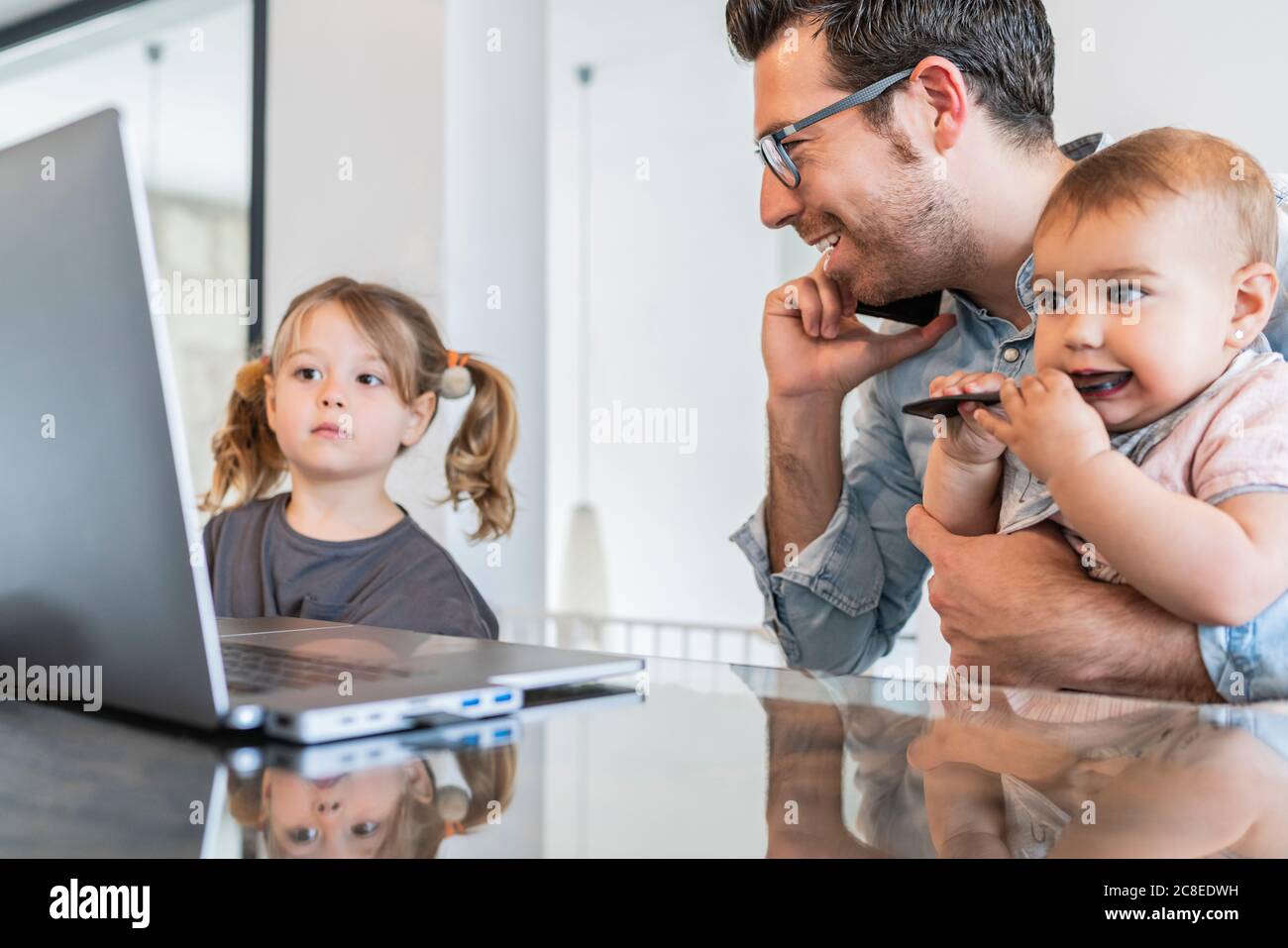 Man holding daughter talking over smart phone while girl looking at ...