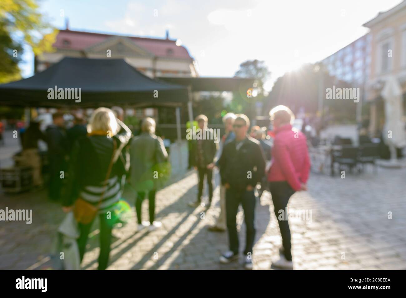 Defocused crowd of people looking busy in front of black canopies in ...