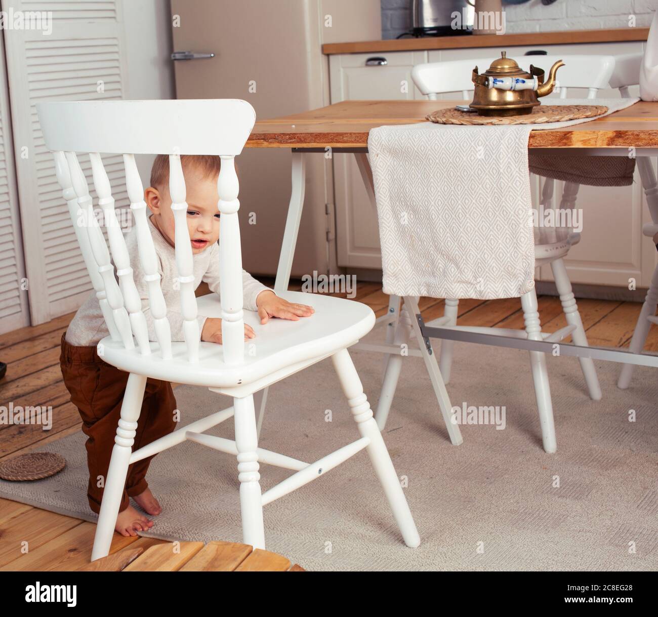 little cute boy with chair on kitchen in morning, lifestyle people ...
