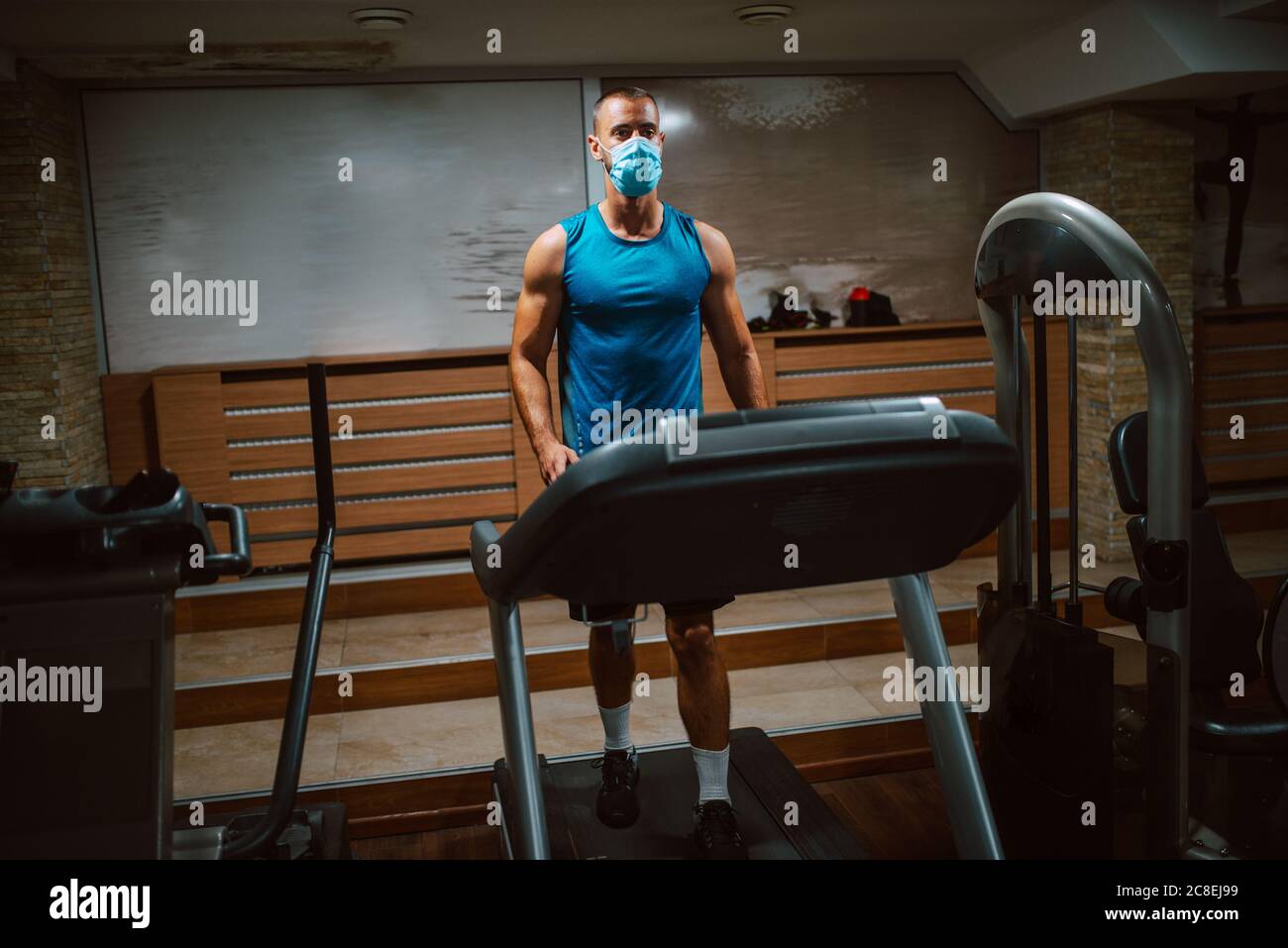 A young muscular caucasian athlete, a man with a medical mask on his ...