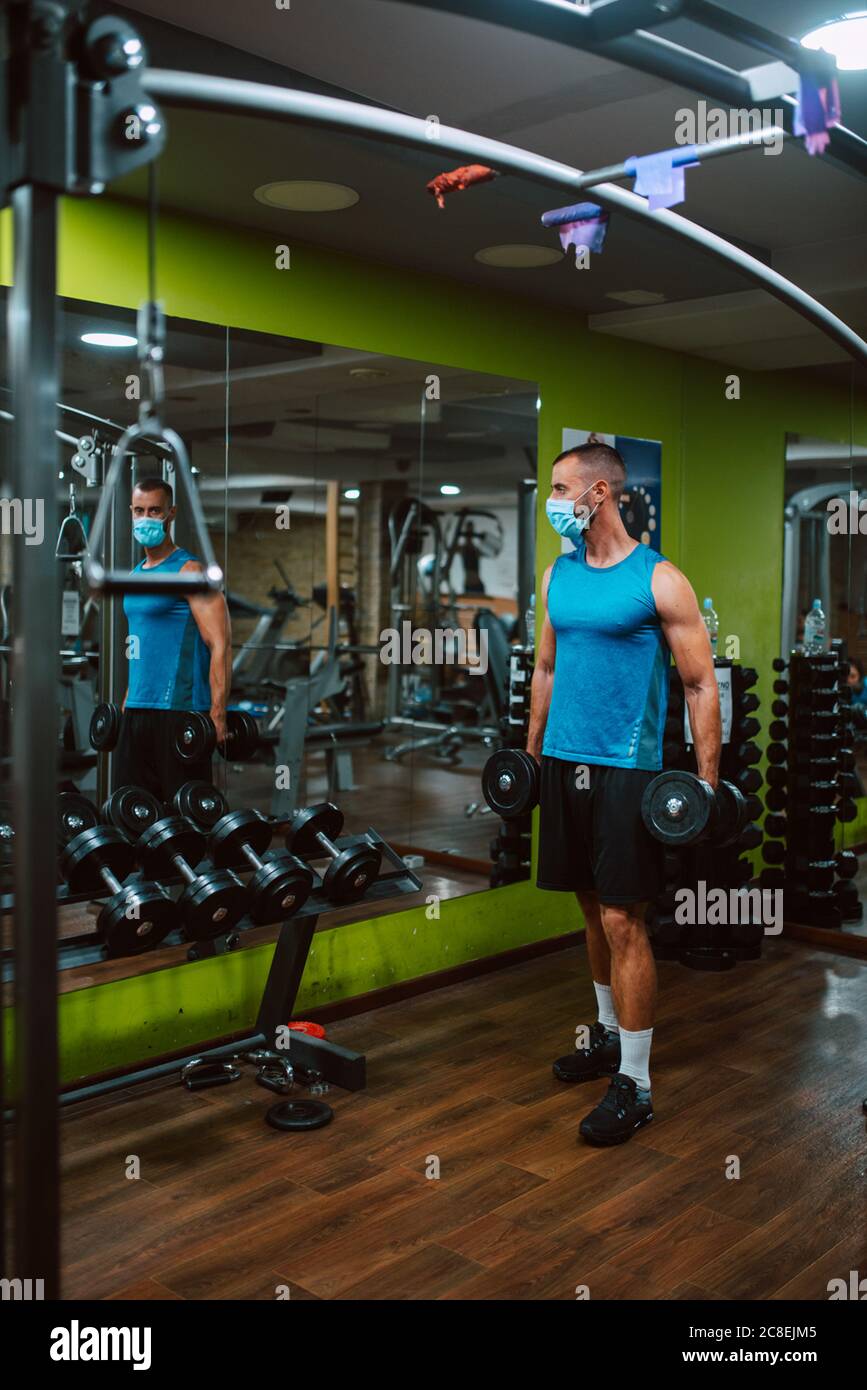 A young caucasian athlete man with a mask on his face exercises and ...