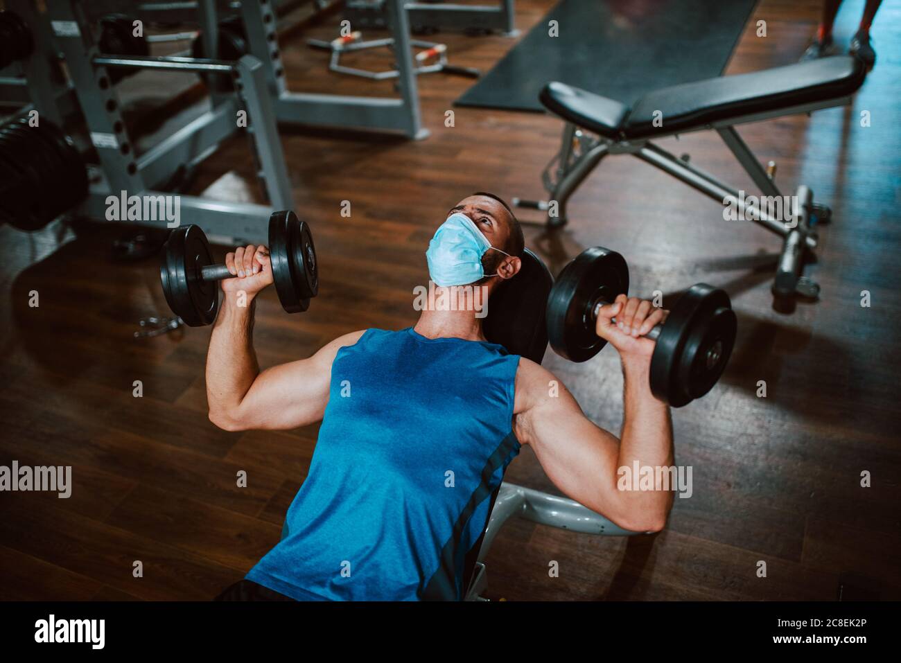 A young caucasian athlete man with a mask on his face exercises and ...
