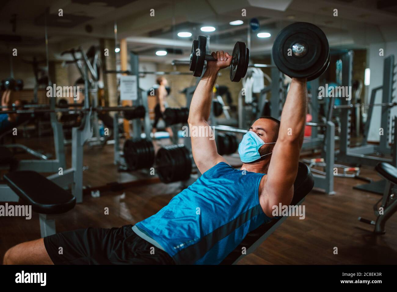 A young caucasian athlete man with a mask on his face exercises and ...