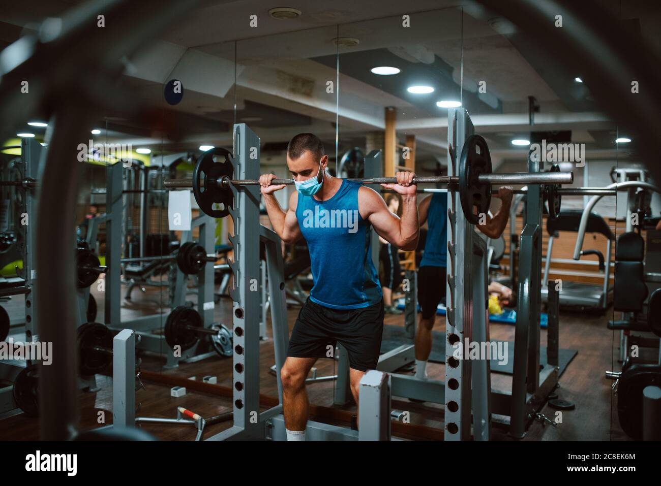 A young caucasian athlete man with a mask on his face exercises and ...