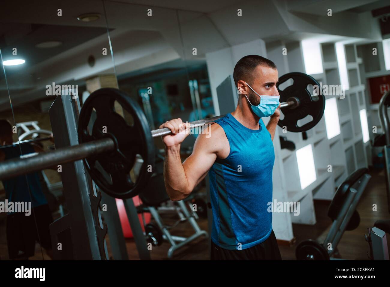 A young caucasian athlete man with a mask on his face exercises and ...