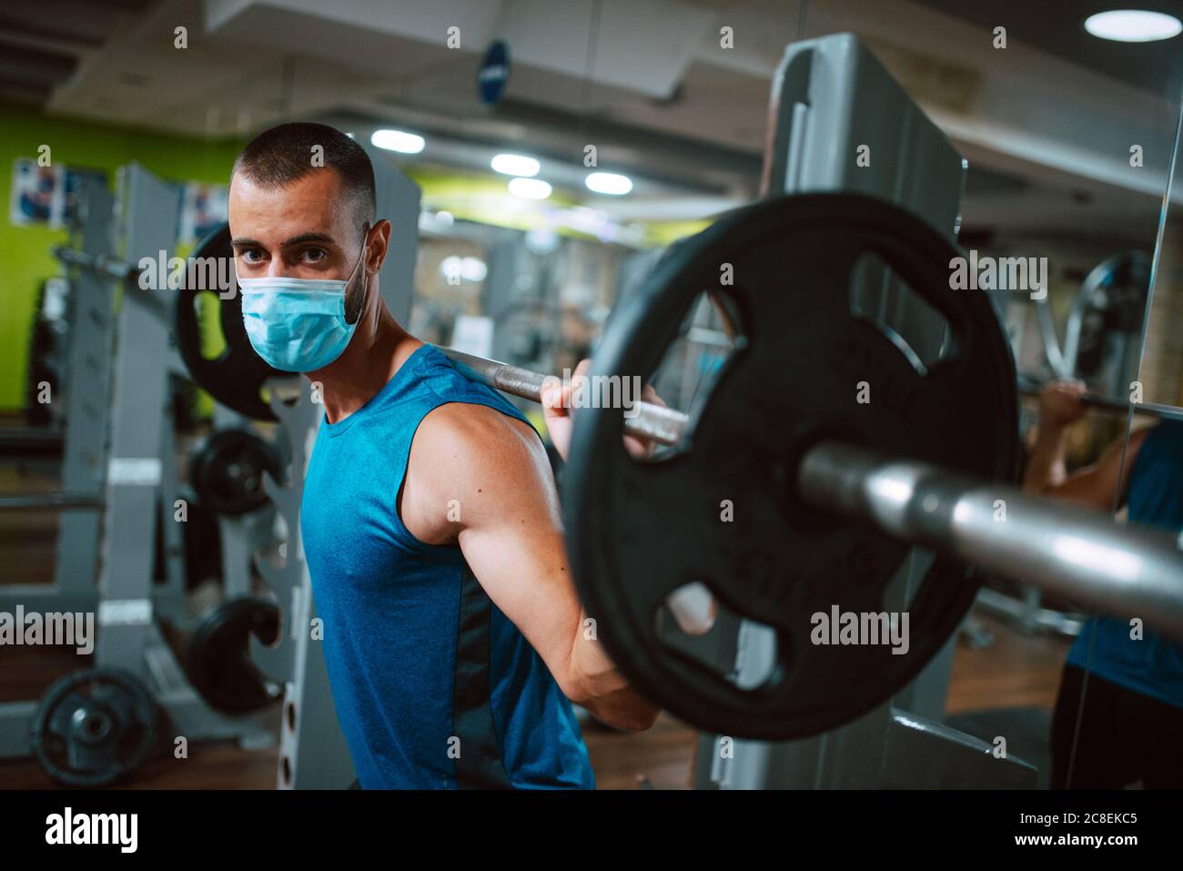 A young caucasian athlete man with a mask on his face exercises and ...