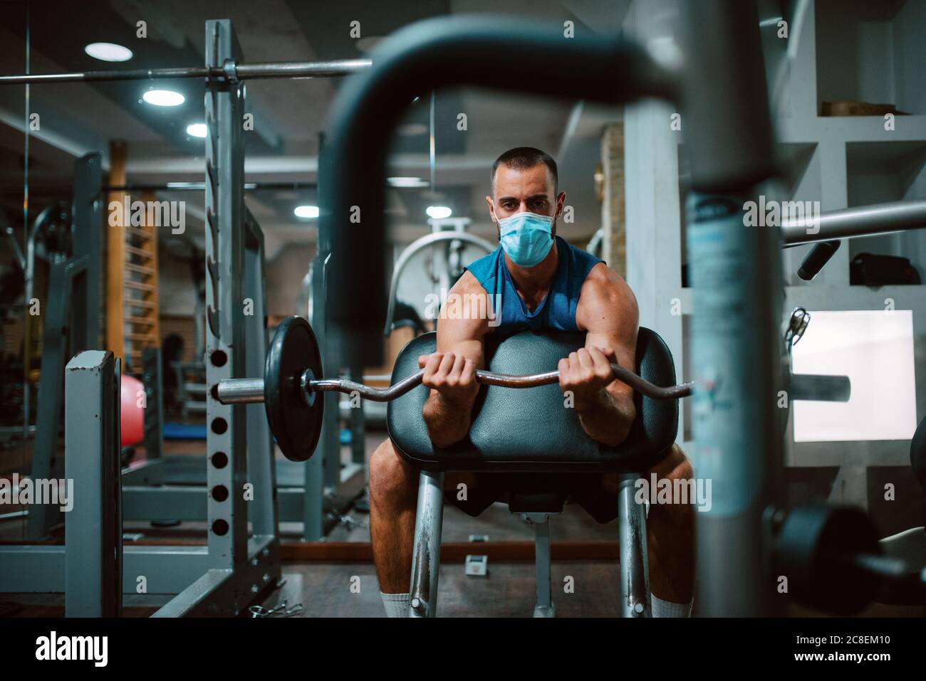 A young caucasian athlete man with a mask on his face exercises and ...