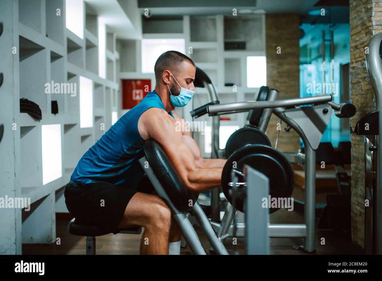 A young caucasian athlete man with a mask on his face exercises and ...