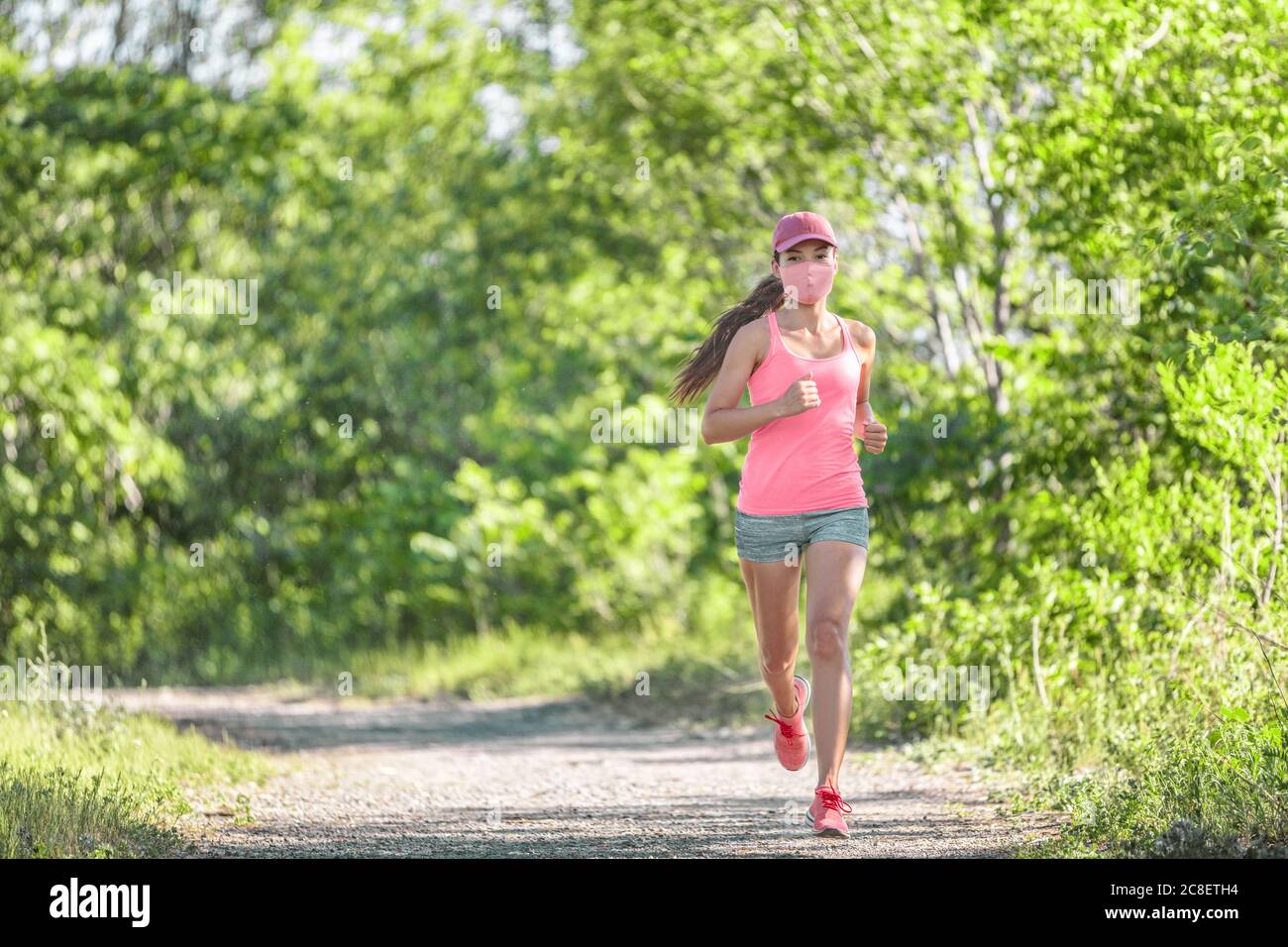 COVID-19 running woman wearing mask while exercising cardio outdoor on ...