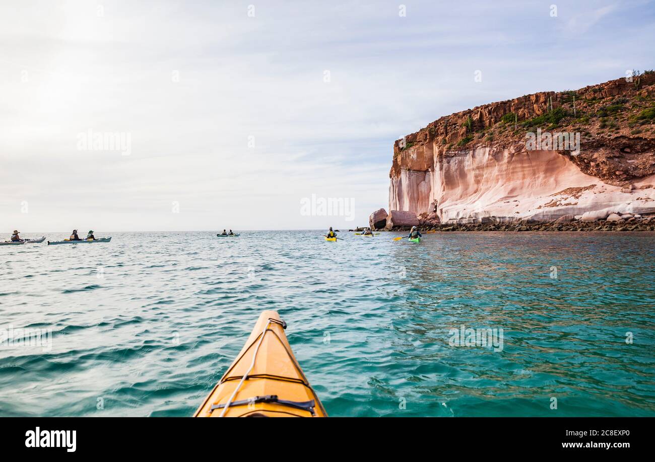 A guided sea kayaking tour offshore below towering sandstone cliffs on ...