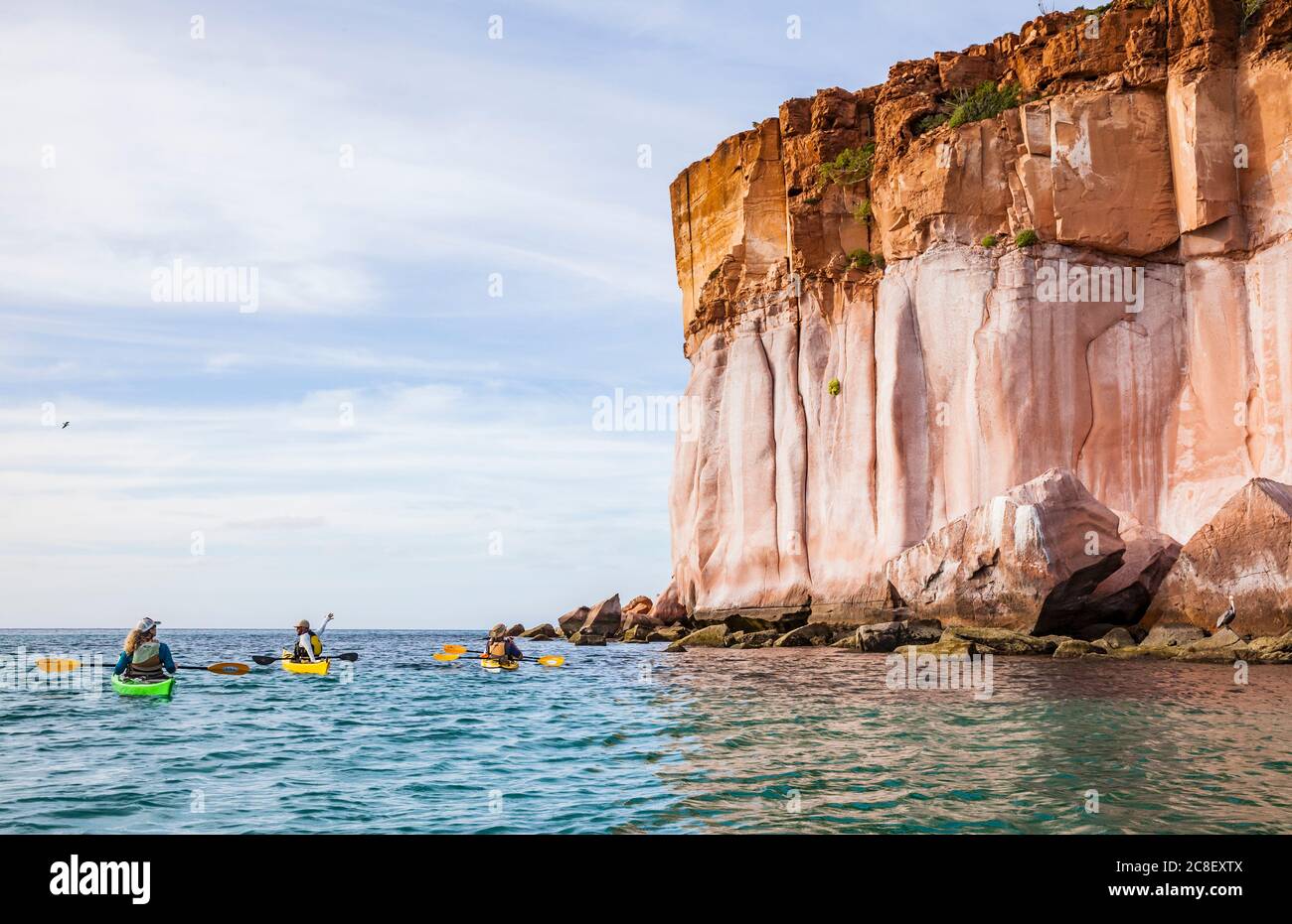 A guided sea kayaking tour offshore below towering sandstone cliffs on ...