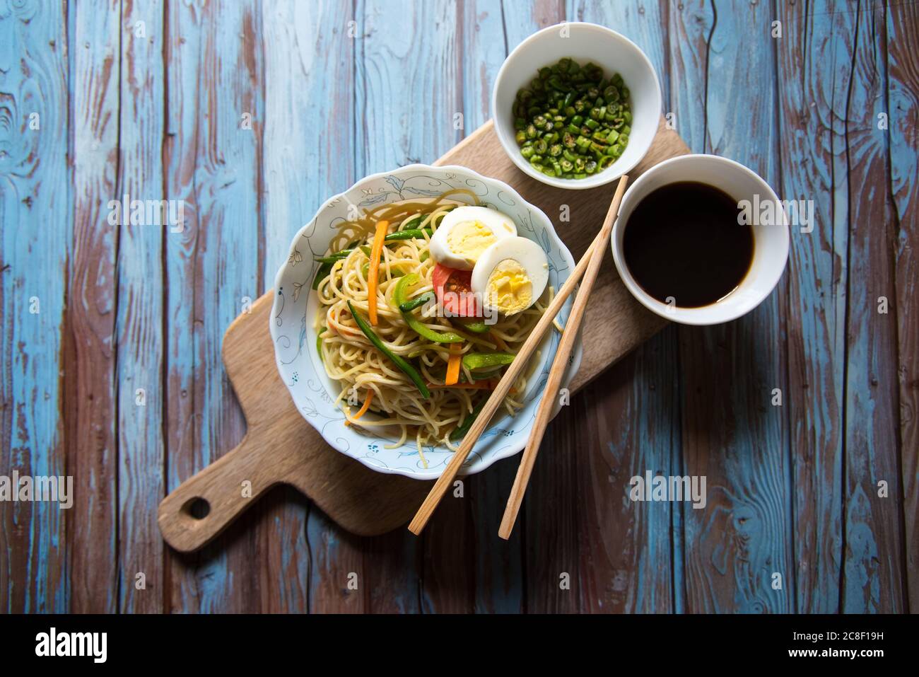 Noodles on a wooden platter with condiments Stock Photo - Alamy