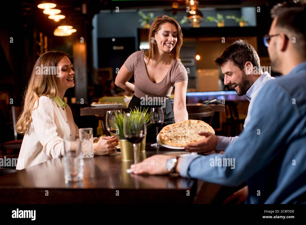 Smiling waitress serving pizza hi-res stock photography and images - Alamy