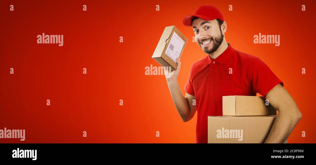 funny delivery service man with box in hand on red background with copy ...