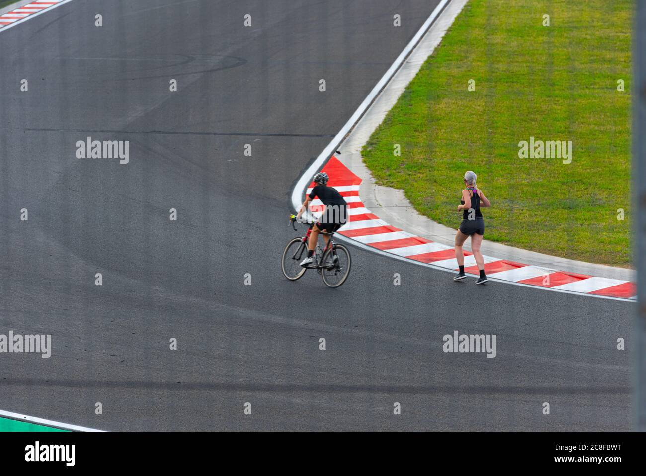 Two persons running and cycling on a race track Stock Photo - Alamy