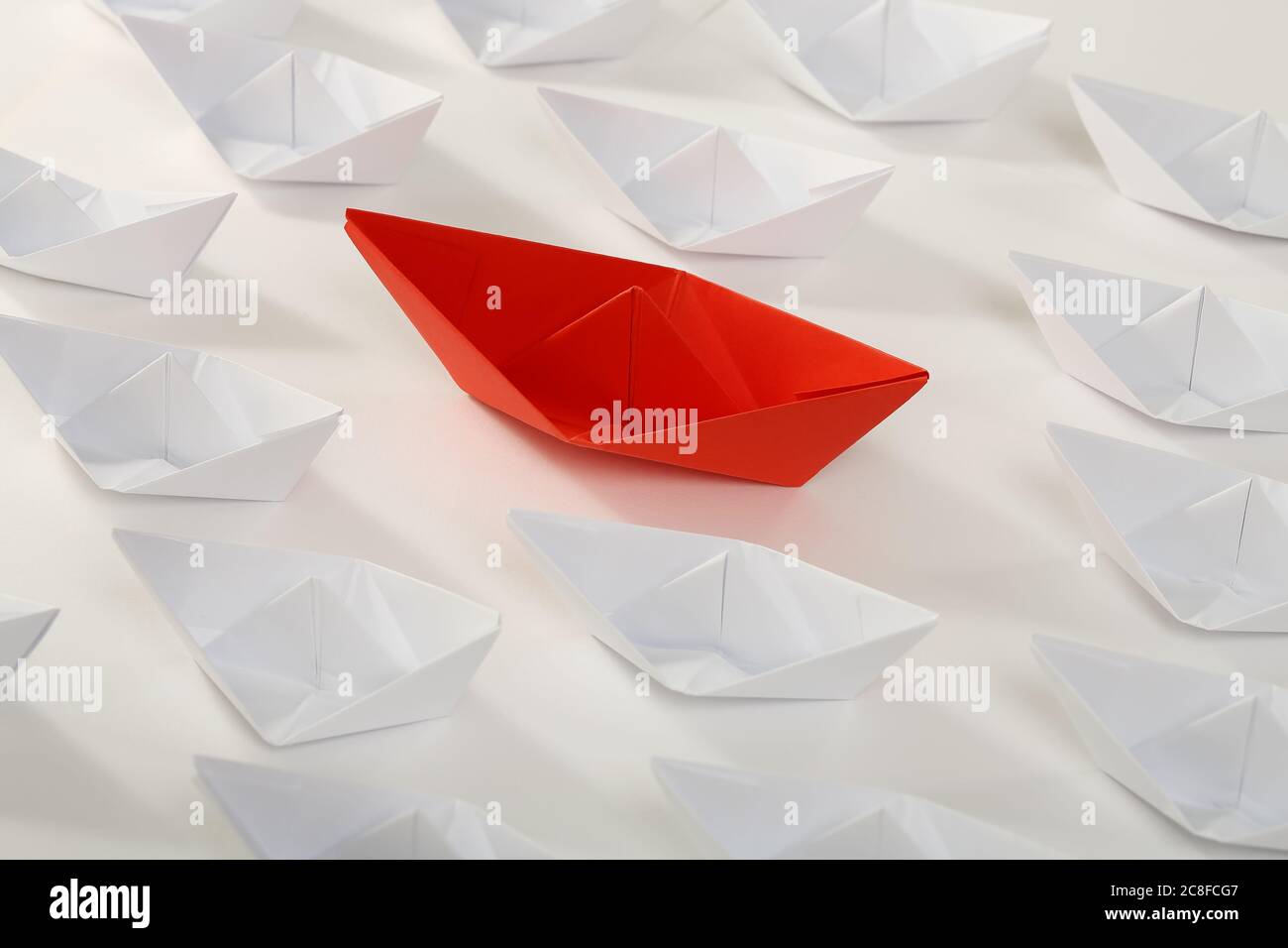 red paper boat among smaller white ones Stock Photo - Alamy