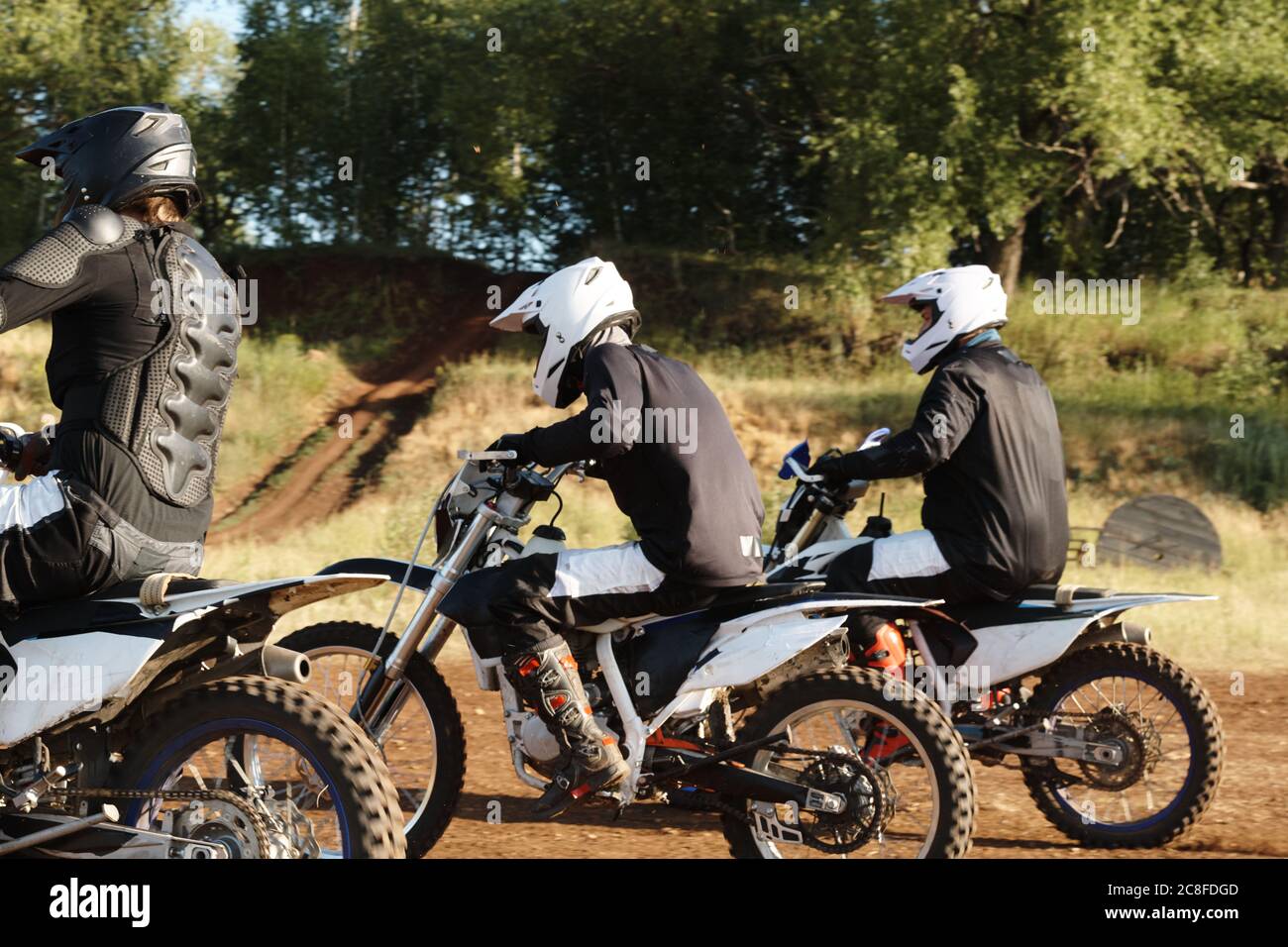 Group of sporty men in helmets enjoying motorcycle racing at off-road ...