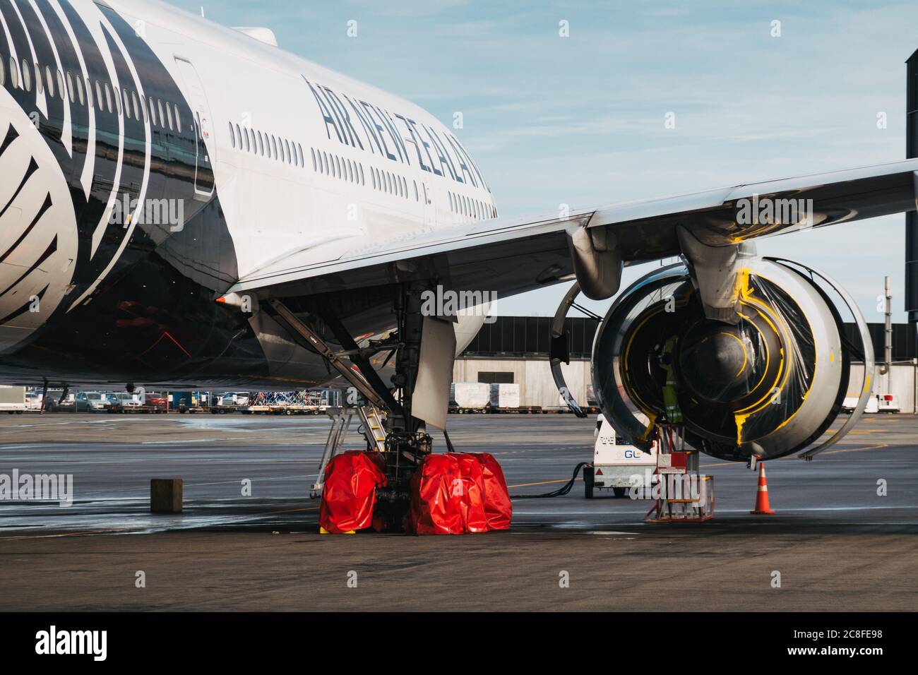 An engineer works on a Boeing 777 engine while the aircraft is parked ...