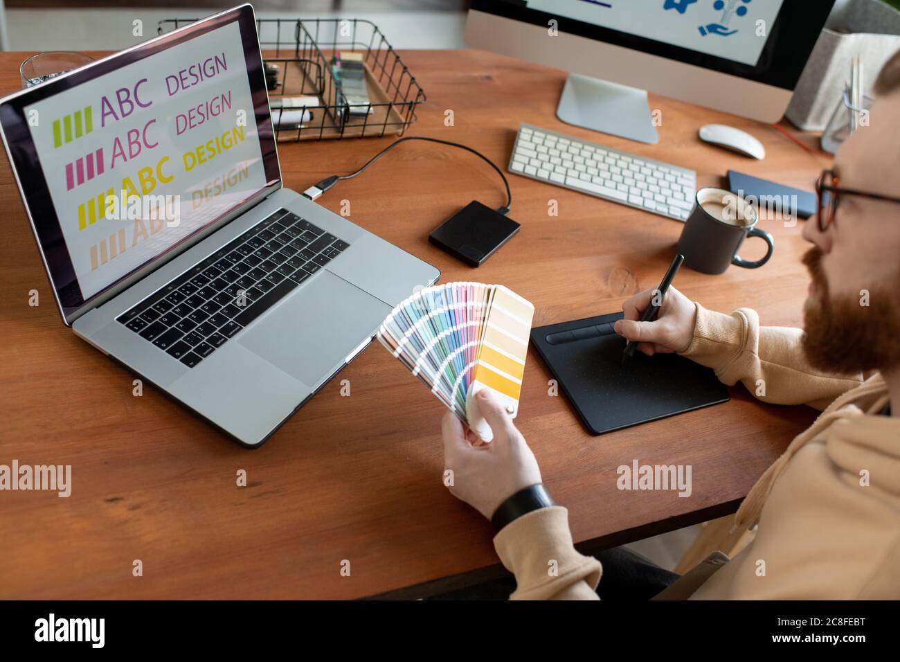 Concentrated male designer writing text on drawing pad and choosing ...