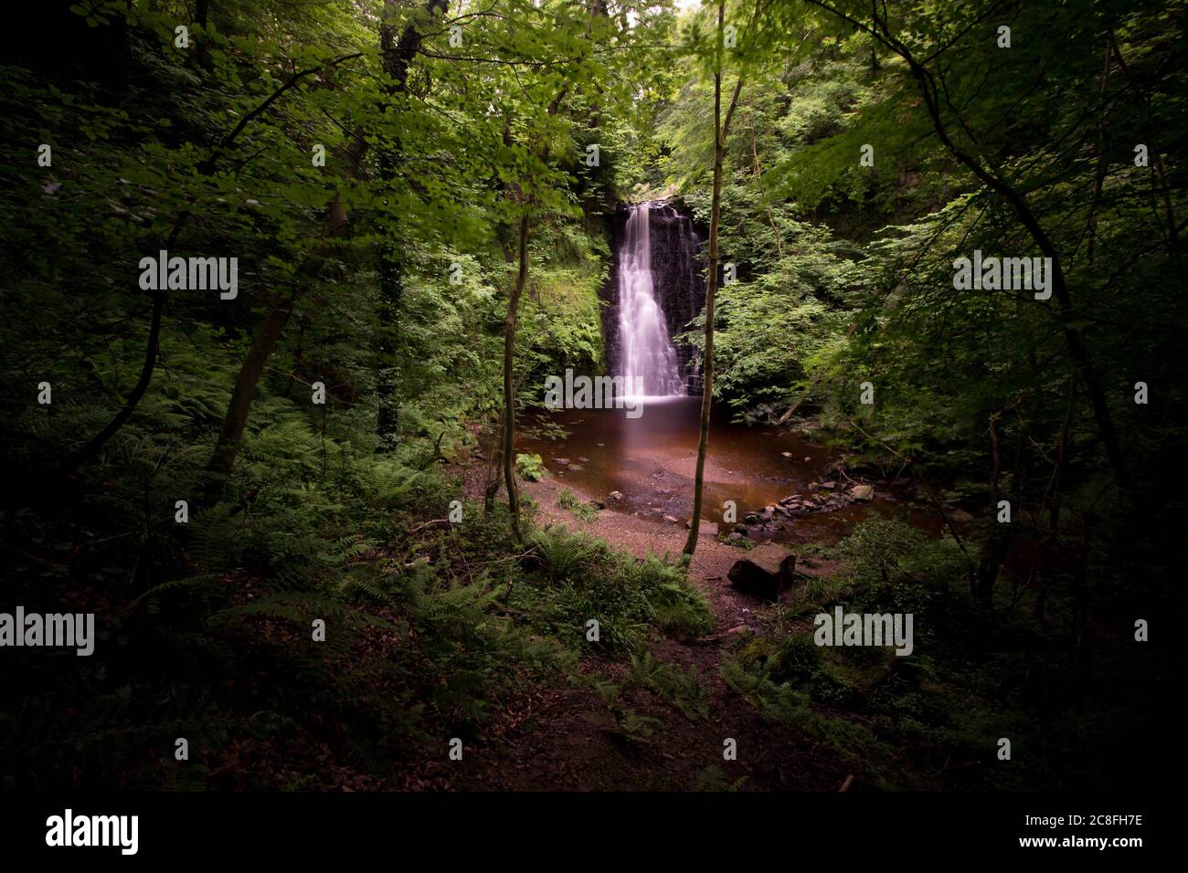Large cascading waterfall tumbling into a peaceful pool. Falling foss ...