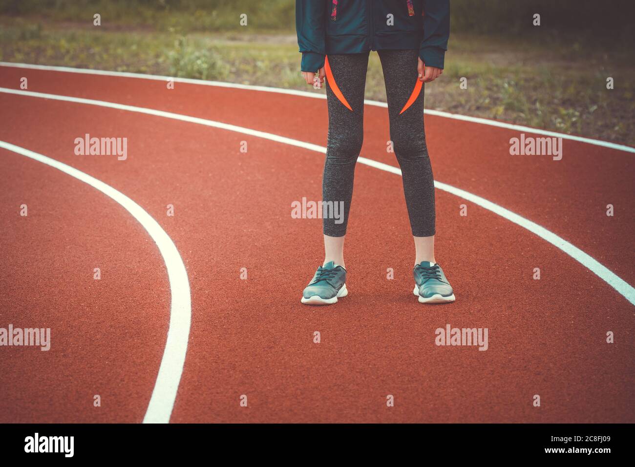 Young runner in sportswear getting ready to run on stadium track with ...