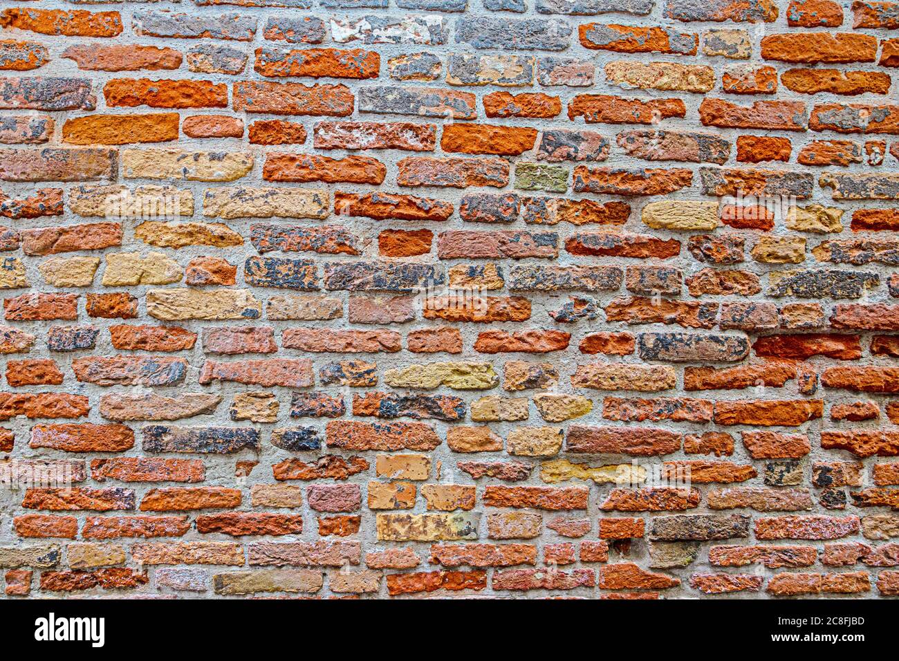 Macro picture of red colored natural brick wall with grey cement joints ...