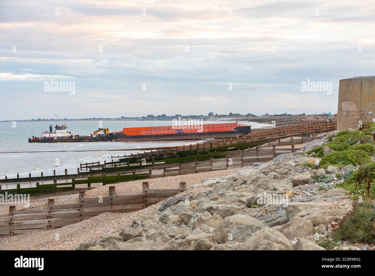 A barge unloading equipment for sea defense work near Hythe in Kent, UK ...