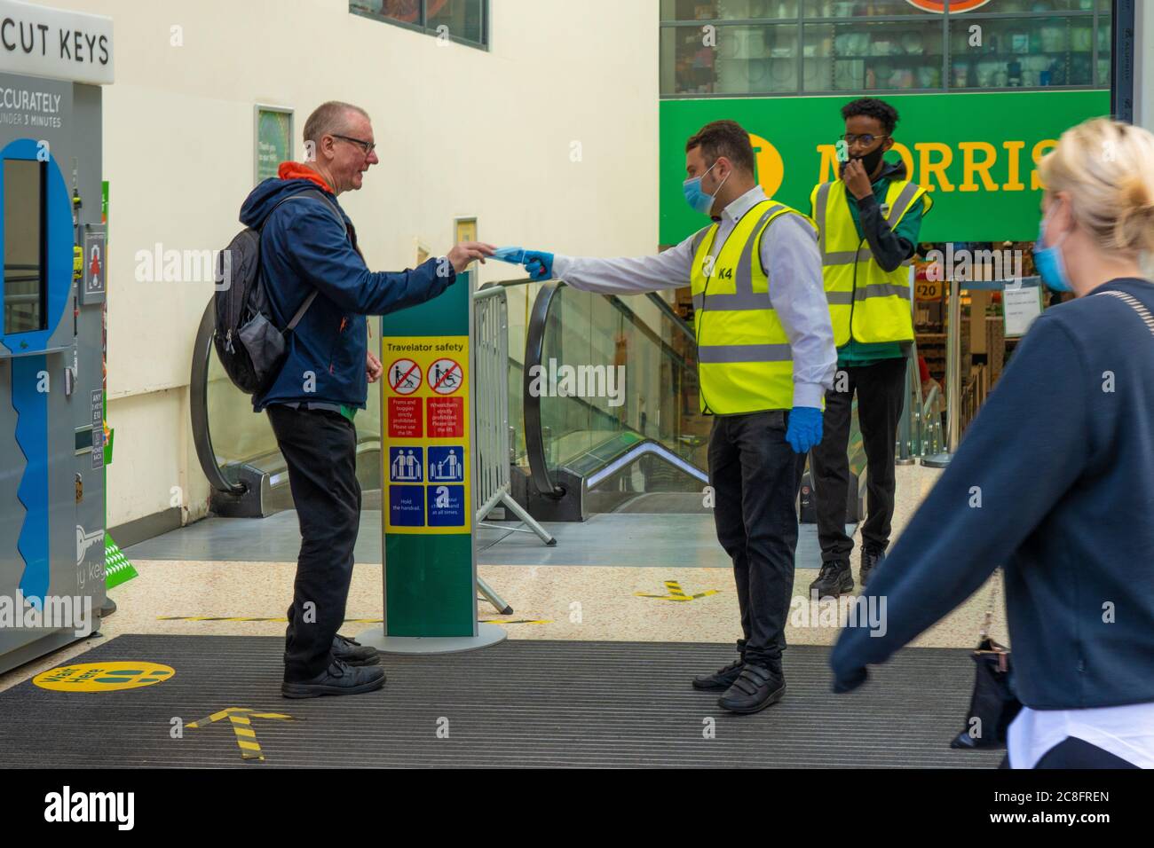 London, UK. Friday, 24 July, 2020. A shopper is handed a protective ...