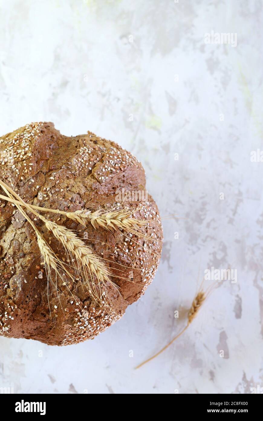 Rustic baked cereal bread with wheat ears, view from above on light ...
