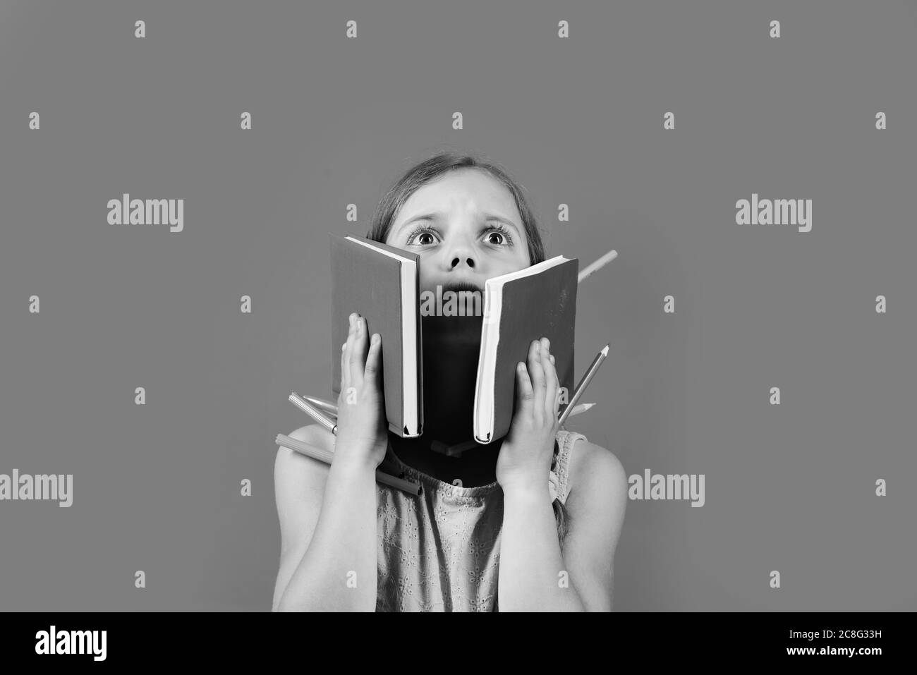 School girl with scared face on salmon red background. Girl holds red ...