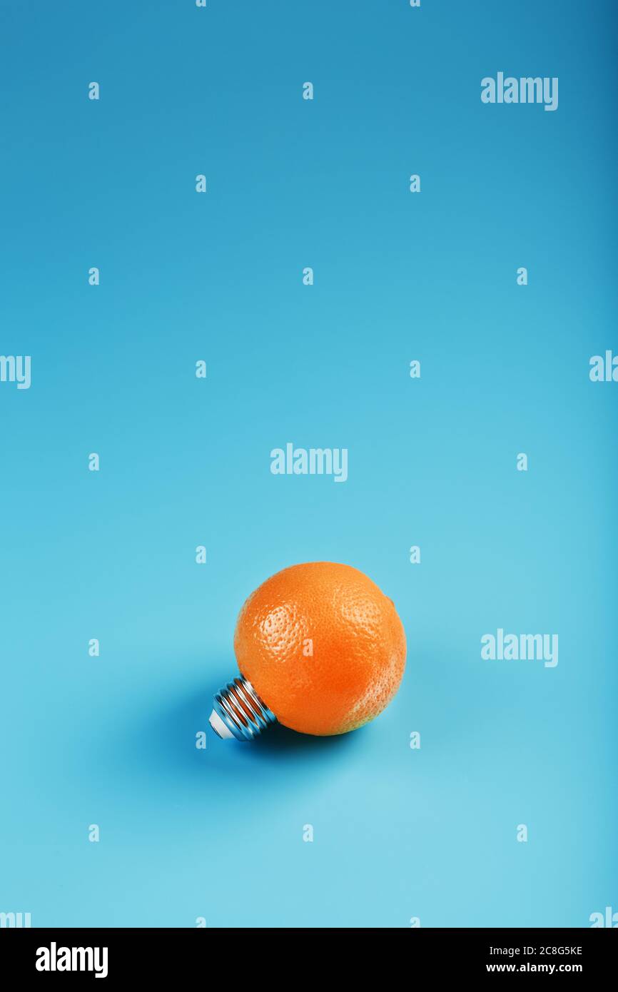 Orange light bulb on a blue background. The concept of fruit ideas ...