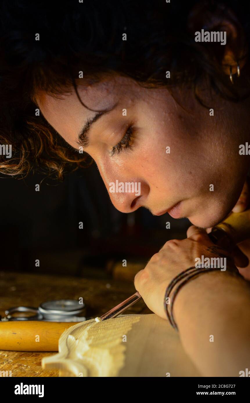 Young attractive female violin maker luthier carving a violin table ...