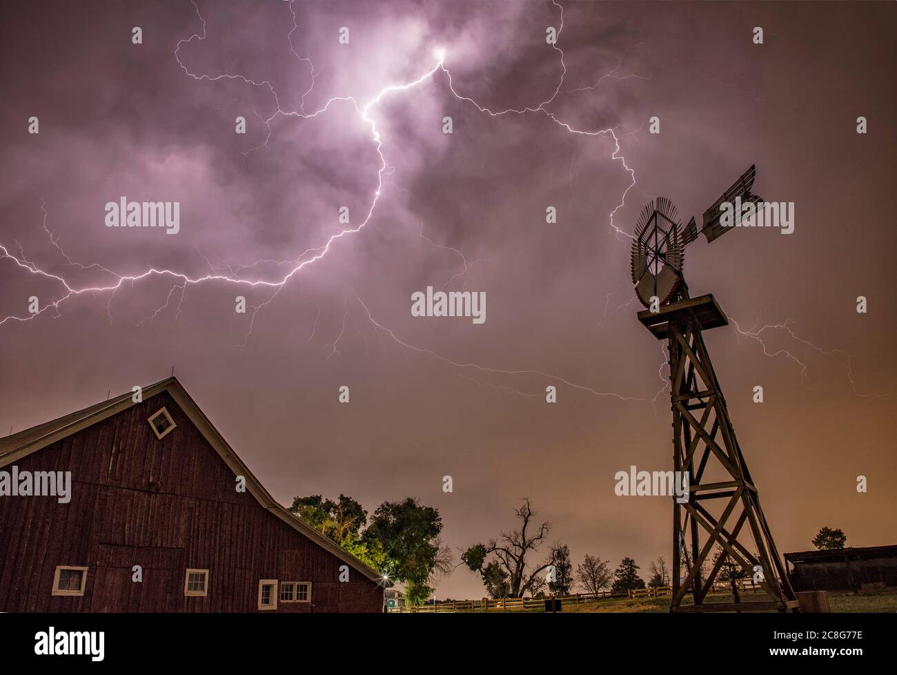 Anvil crawling lightning illuminates an old barn during a thunderstorm ...