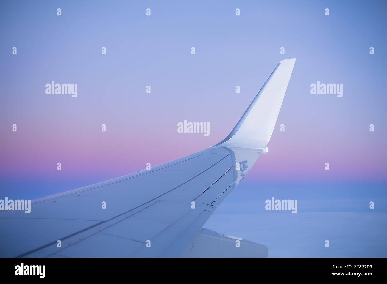 View along passenger plane wing flying above clouds at sunset Stock ...