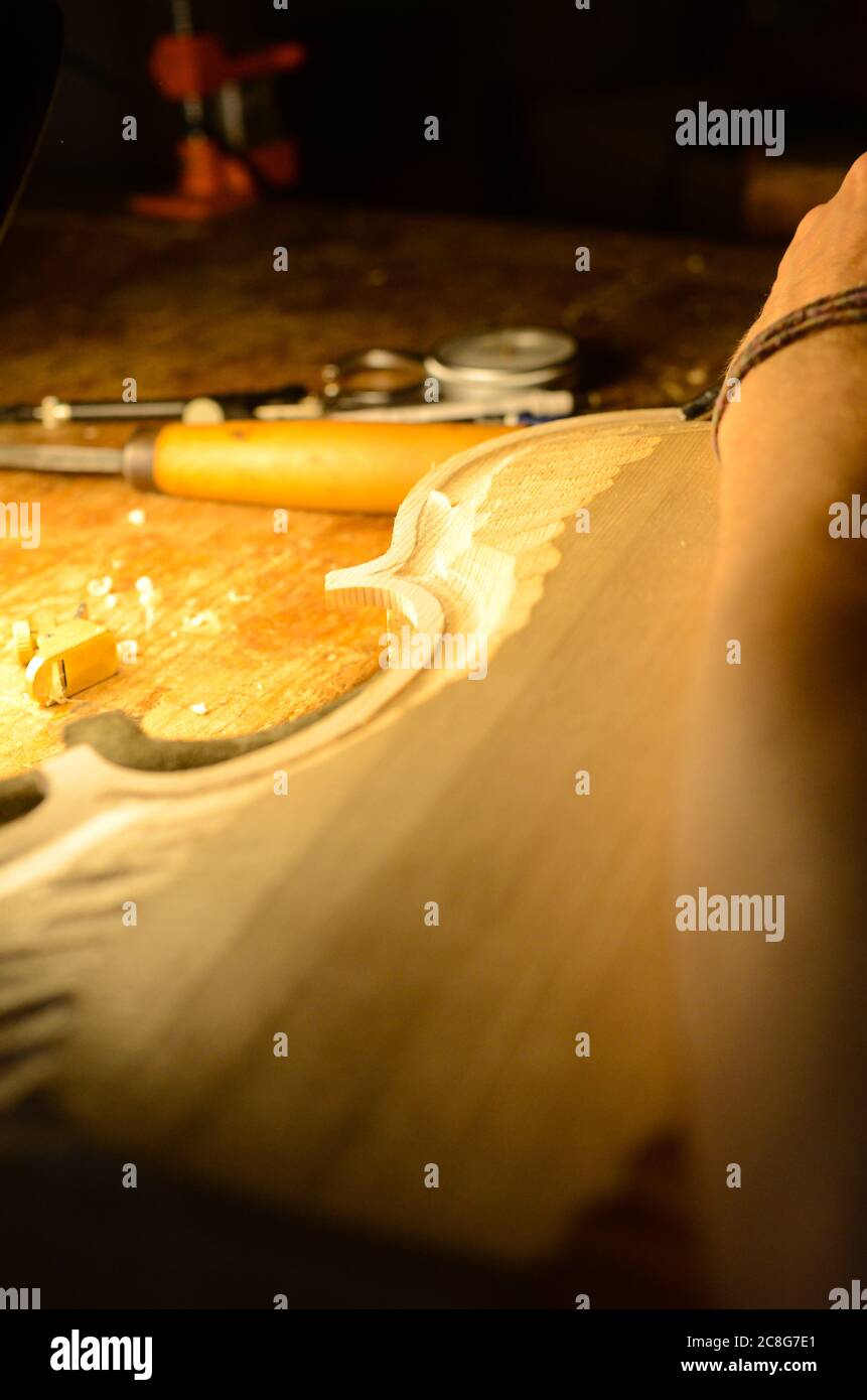 Young attractive female violin maker luthier carving a violin table ...