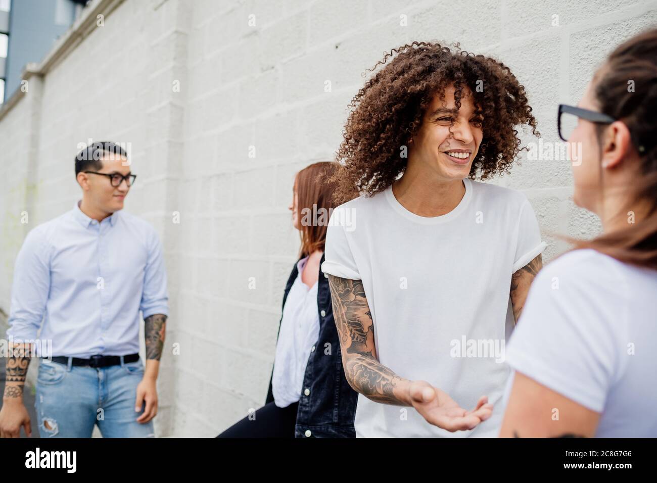 Mixed race group of friends hanging out together in town Stock Photo ...