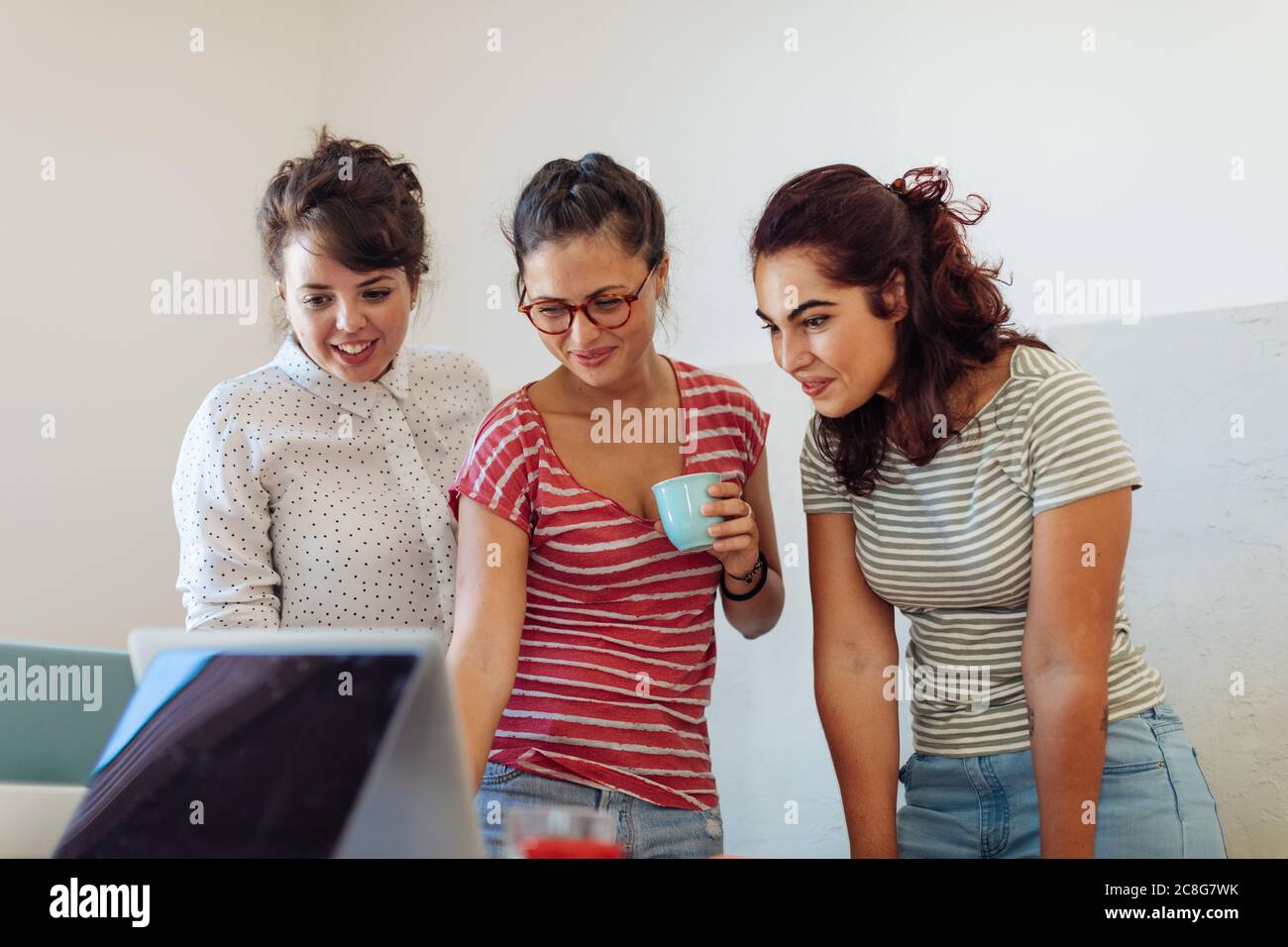 Colleagues using laptop together Stock Photo - Alamy