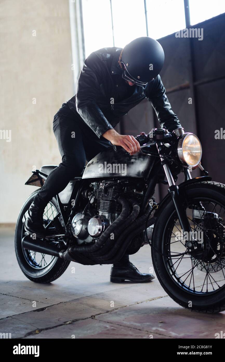 Young male motorcyclist revving vintage motorcycle in garage Stock ...
