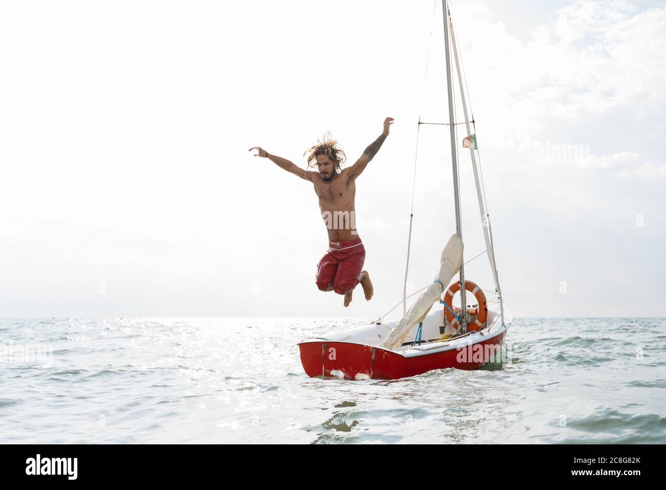 Man jumping off sailboat Stock Photo - Alamy