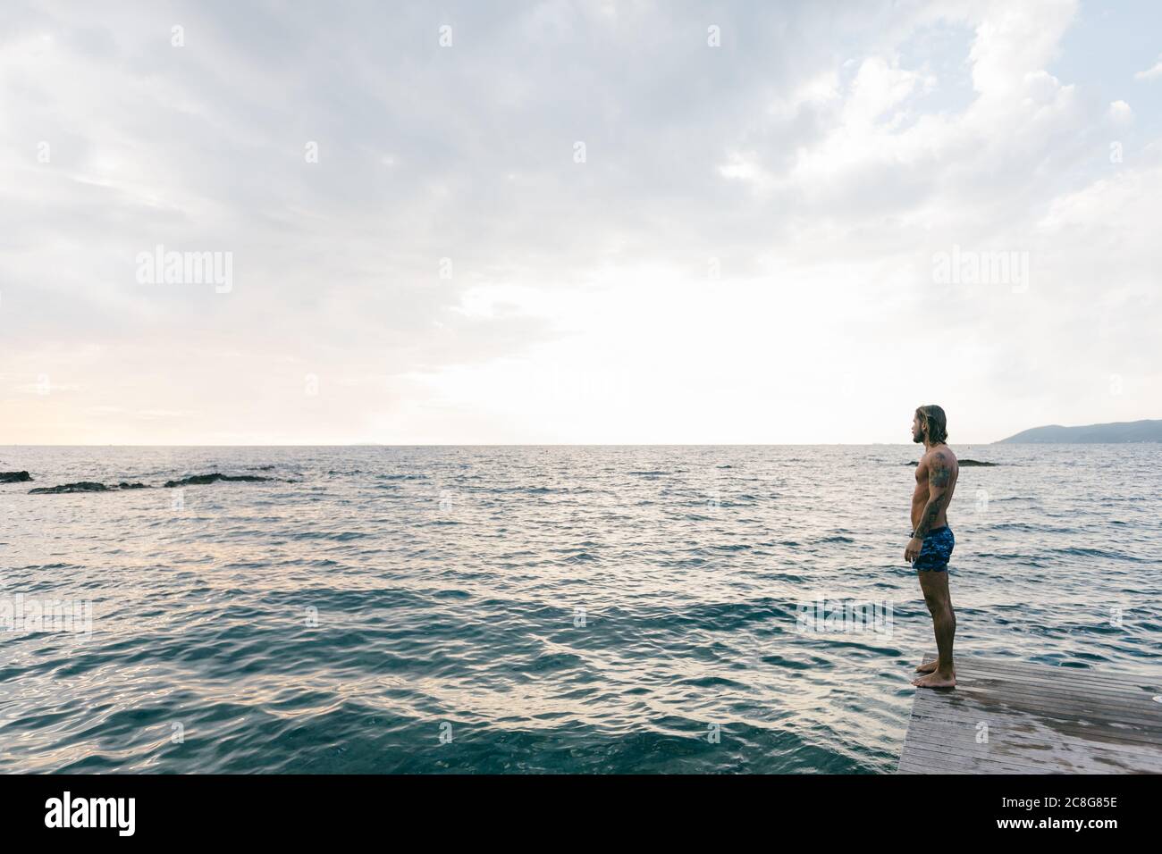 Man standing on edge of sea Stock Photo - Alamy
