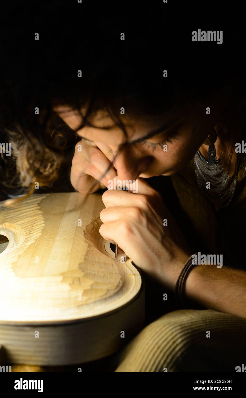 Young attractive female violin maker luthier carving a violin table ...