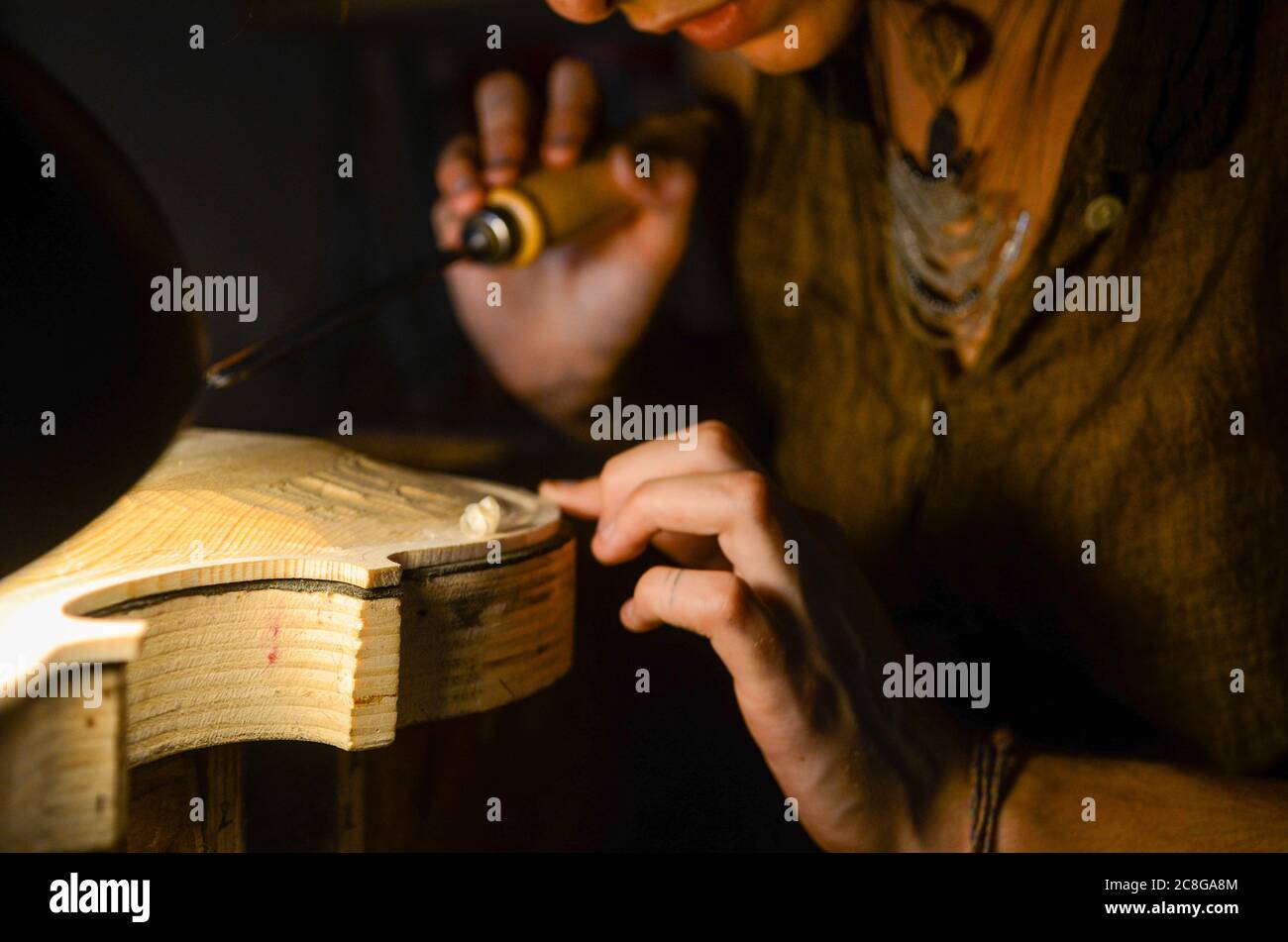 Young attractive female violin maker luthier carving a violin table ...