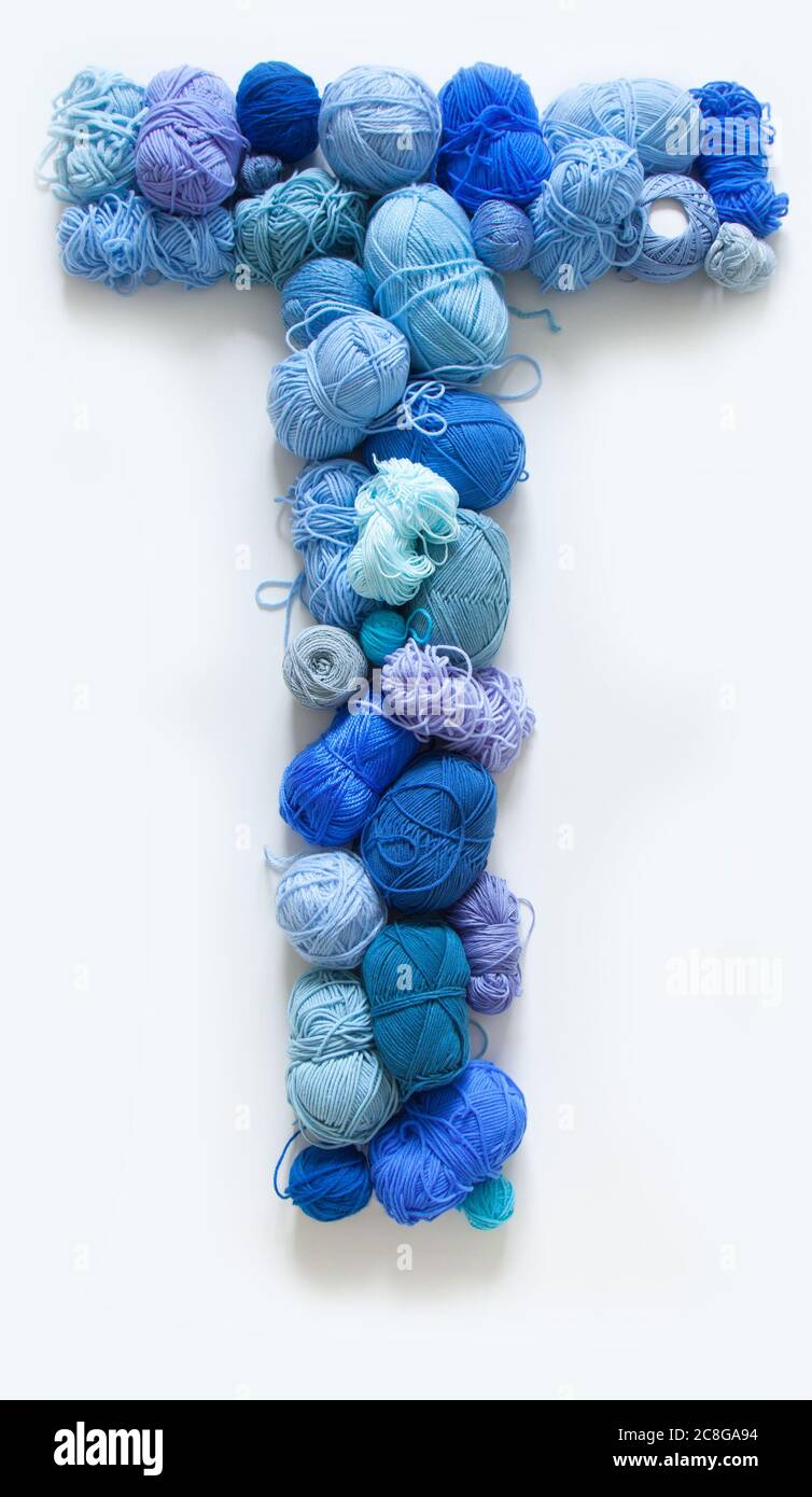 The letter T is made of multi-colored skeins and a ball of yarn. White ...