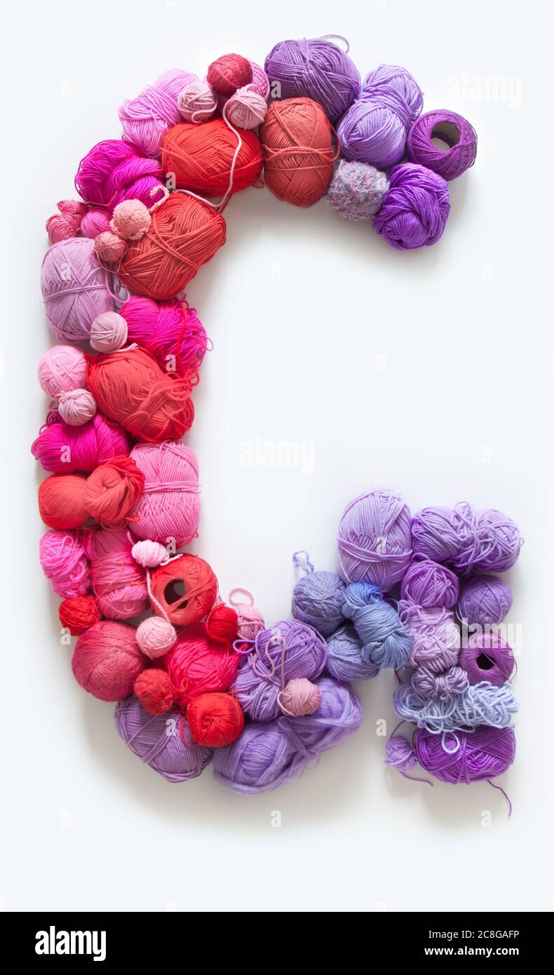 The letter G is made of multi-colored skeins and a ball of yarn. White ...