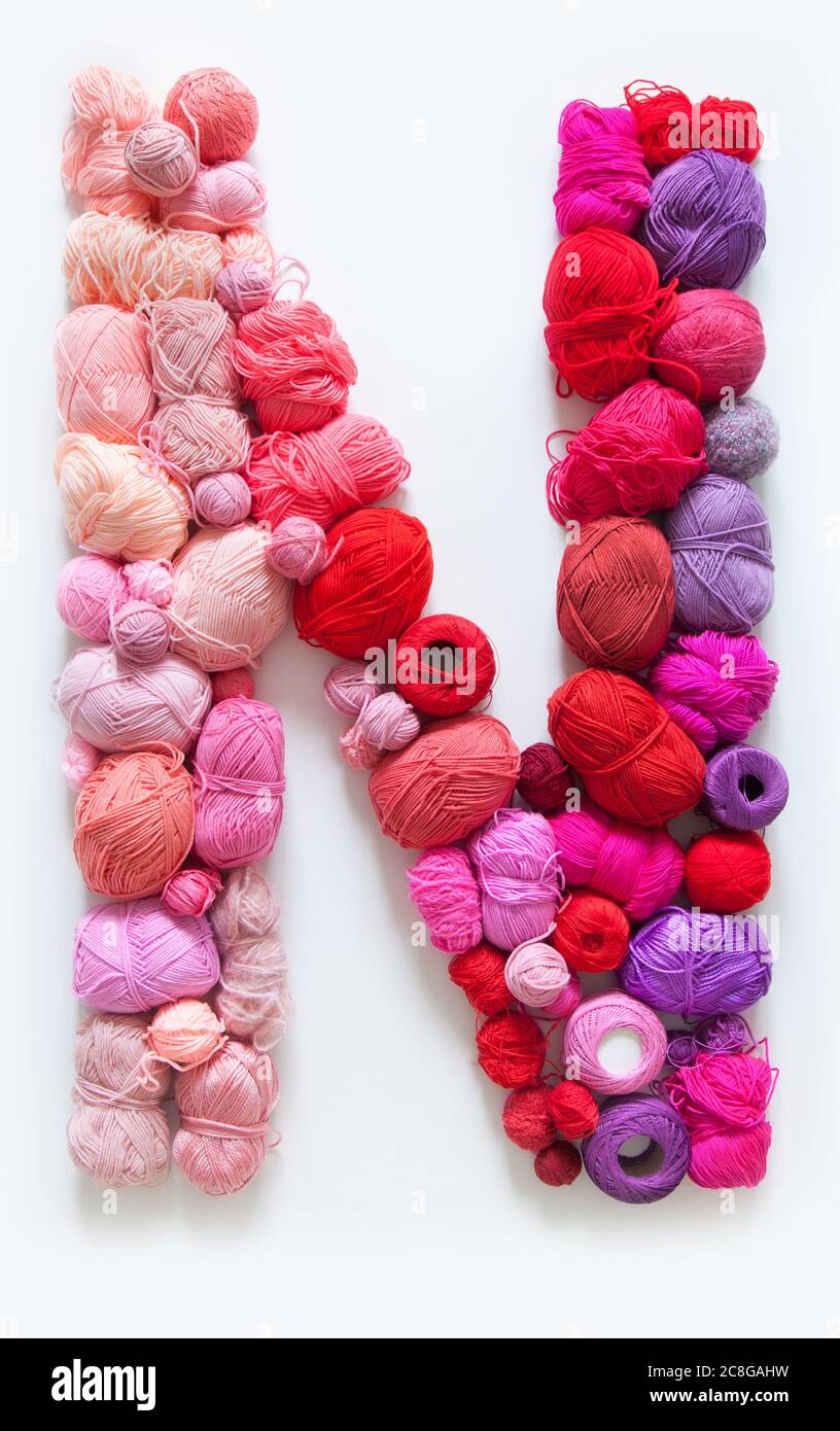 The letter N is made of multi-colored skeins and a ball of yarn. White ...