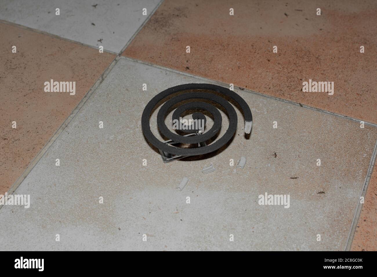 Burning insect mosquito coil on the floor outdoors. Dead mosquitoes lie ...