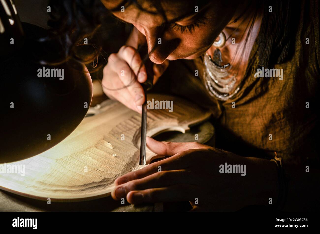 Young attractive female violin maker luthier carving a violin table ...