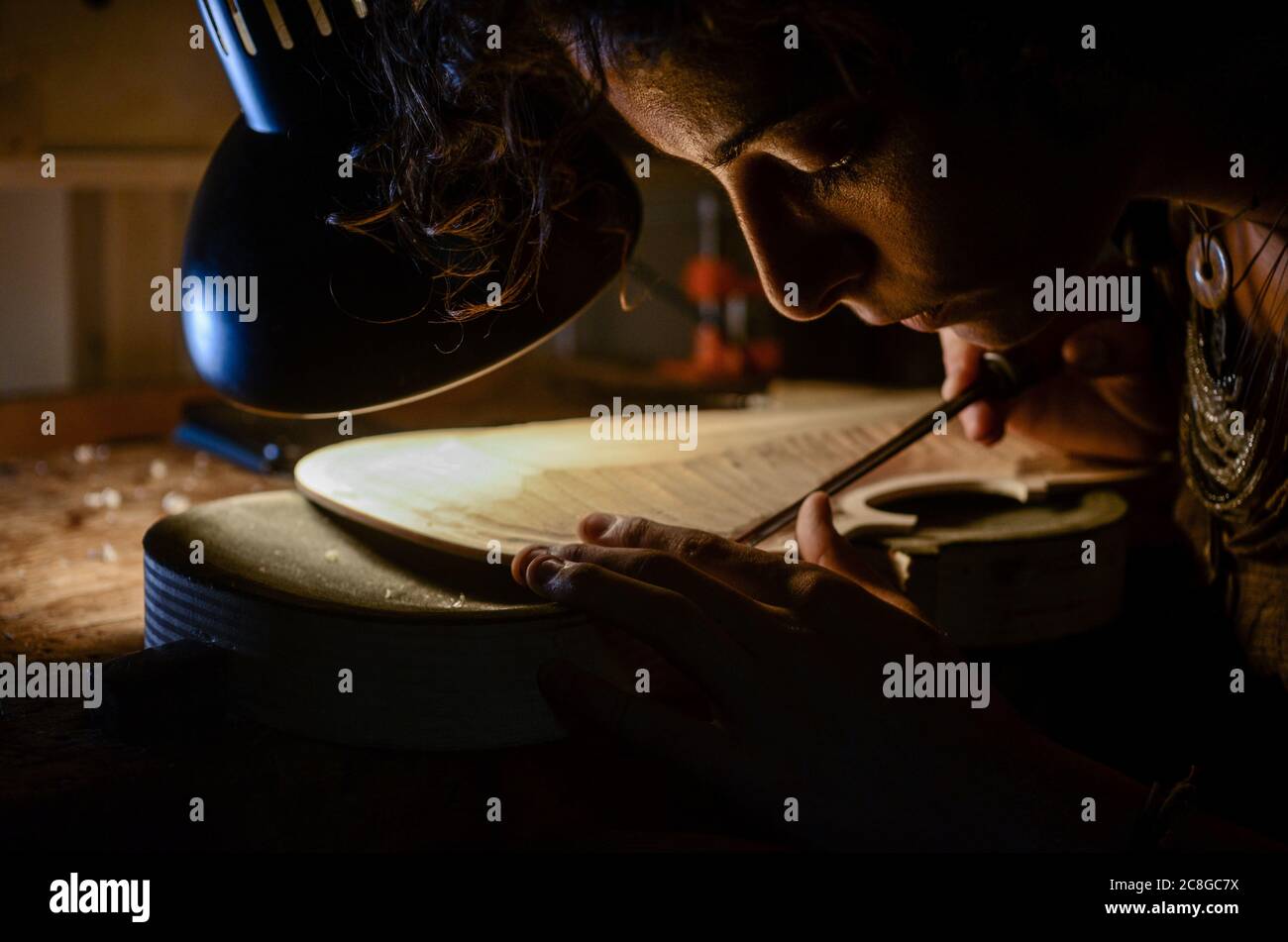 Young attractive female violin maker luthier carving a violin table ...